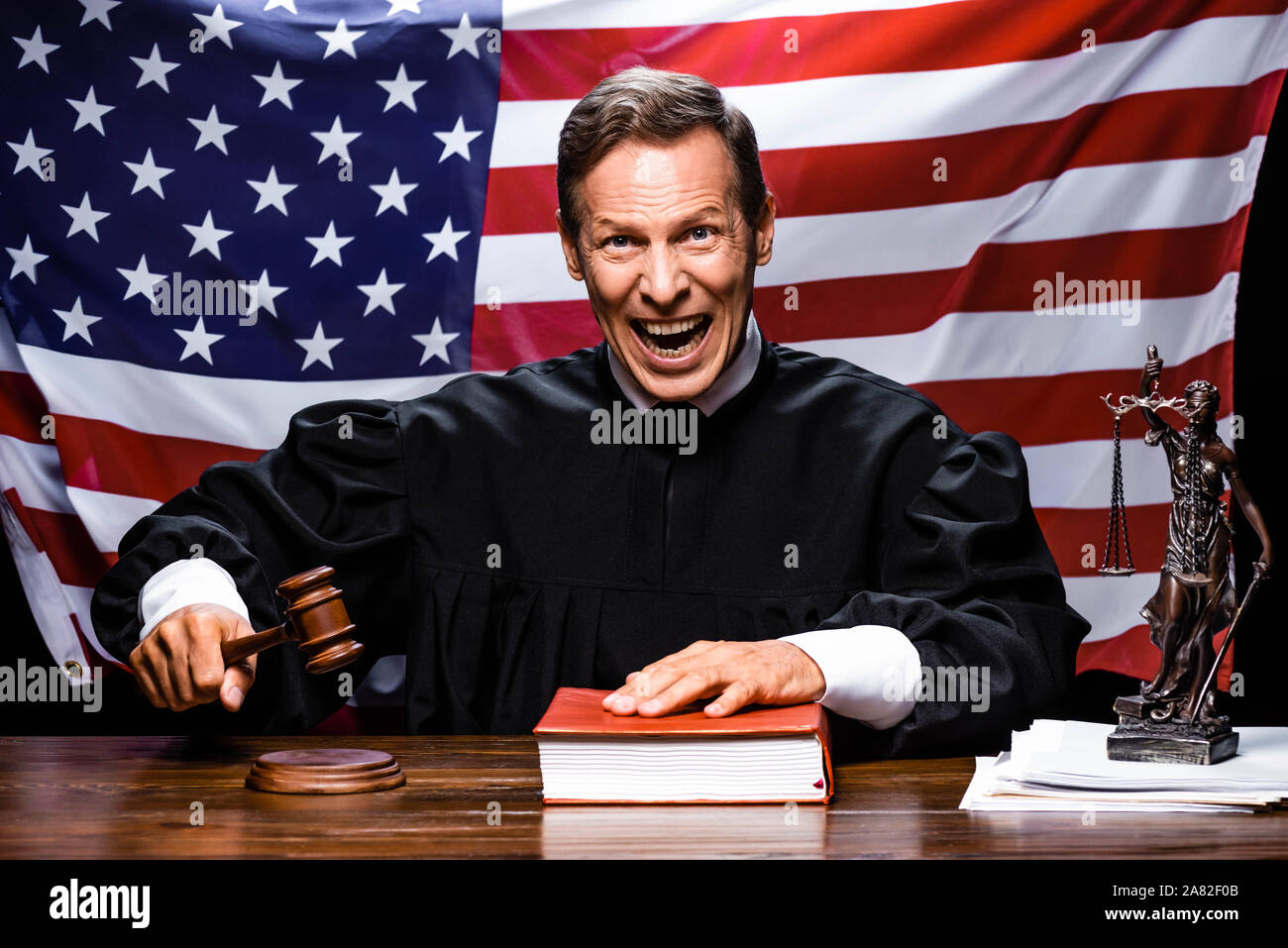 angry judge in judicial robe hitting gavel and putting hand on book ...