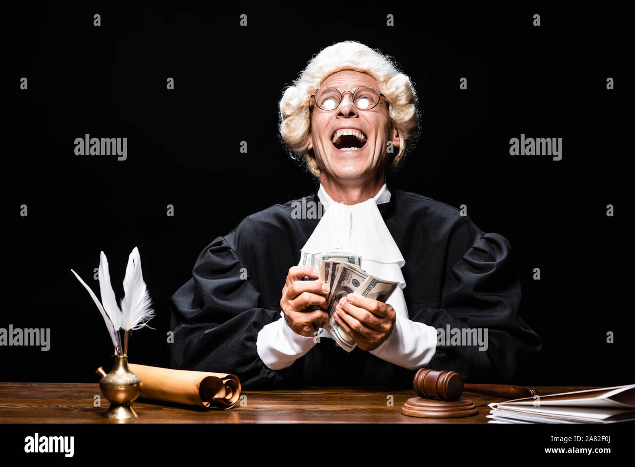 smiling judge in judicial robe and wig sitting at table and holding ...