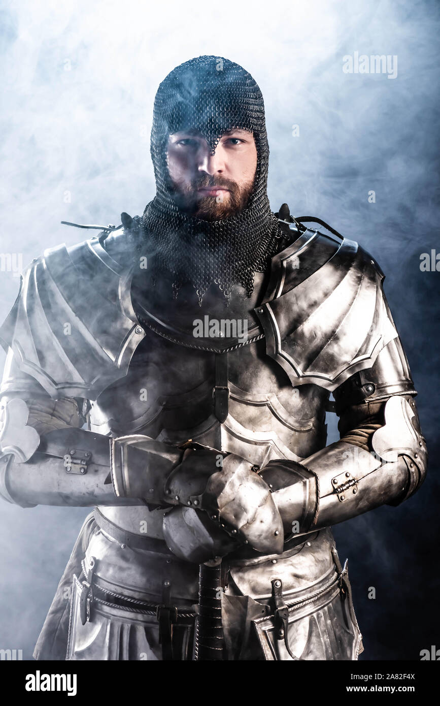 handsome knight in armor looking at camera on black background Stock ...