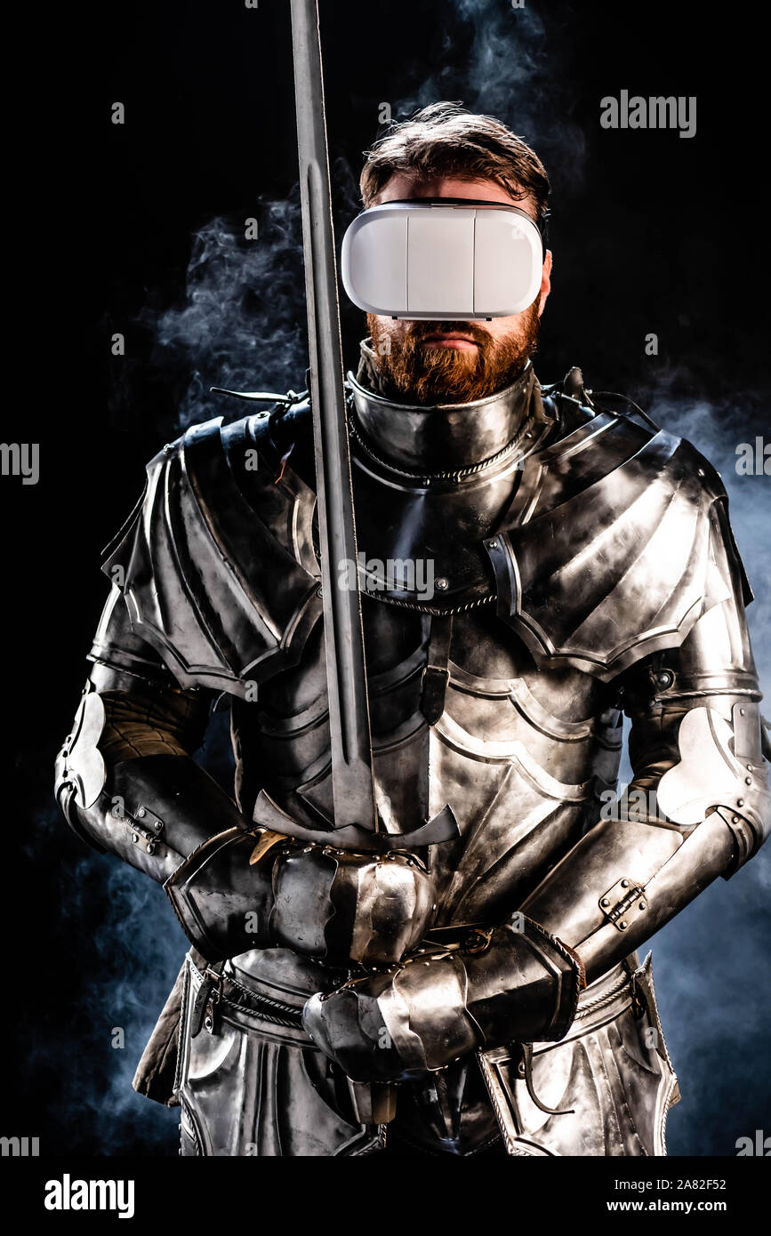 knight with virtual reality headset in armor holding sword on black ...