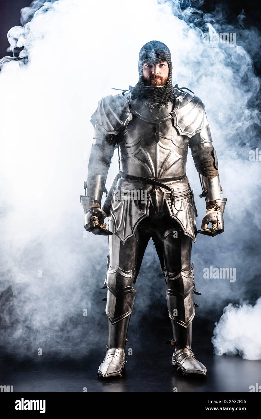 handsome knight in armor looking at camera on black background Stock ...