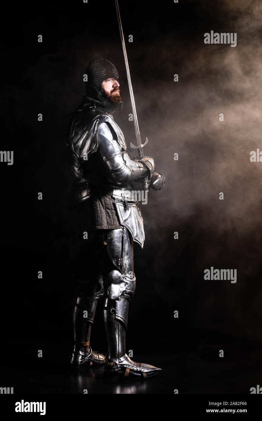 handsome knight in armor holding sword on black background Stock Photo ...