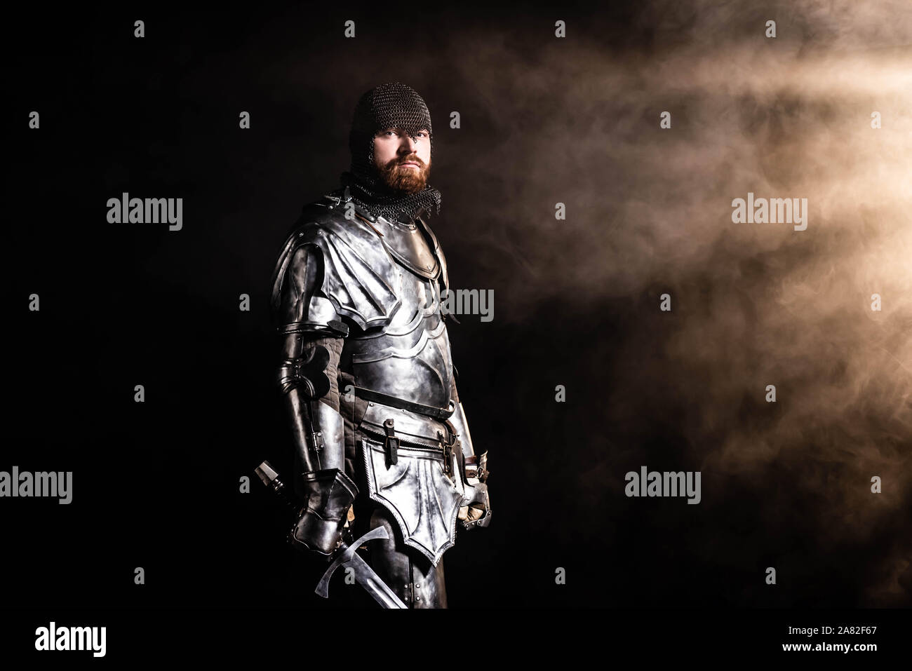 handsome knight in armor holding sword on black background Stock Photo ...