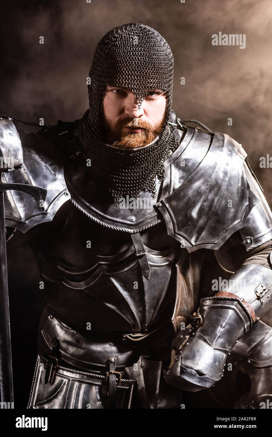 handsome knight in armor holding sword on black background Stock Photo ...