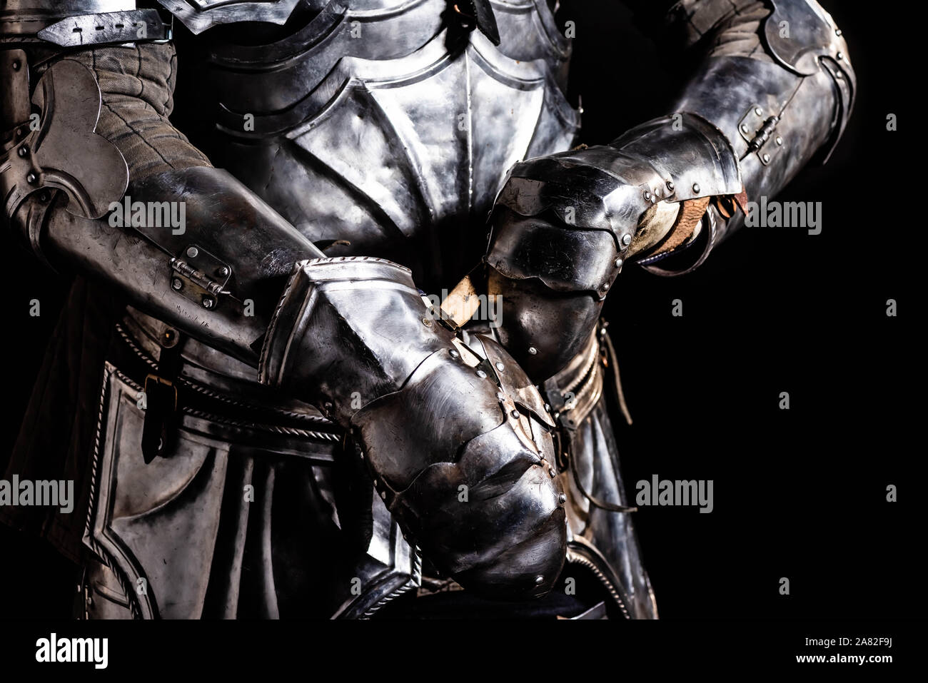 cropped view of knight in armor holding sword isolated on black Stock ...