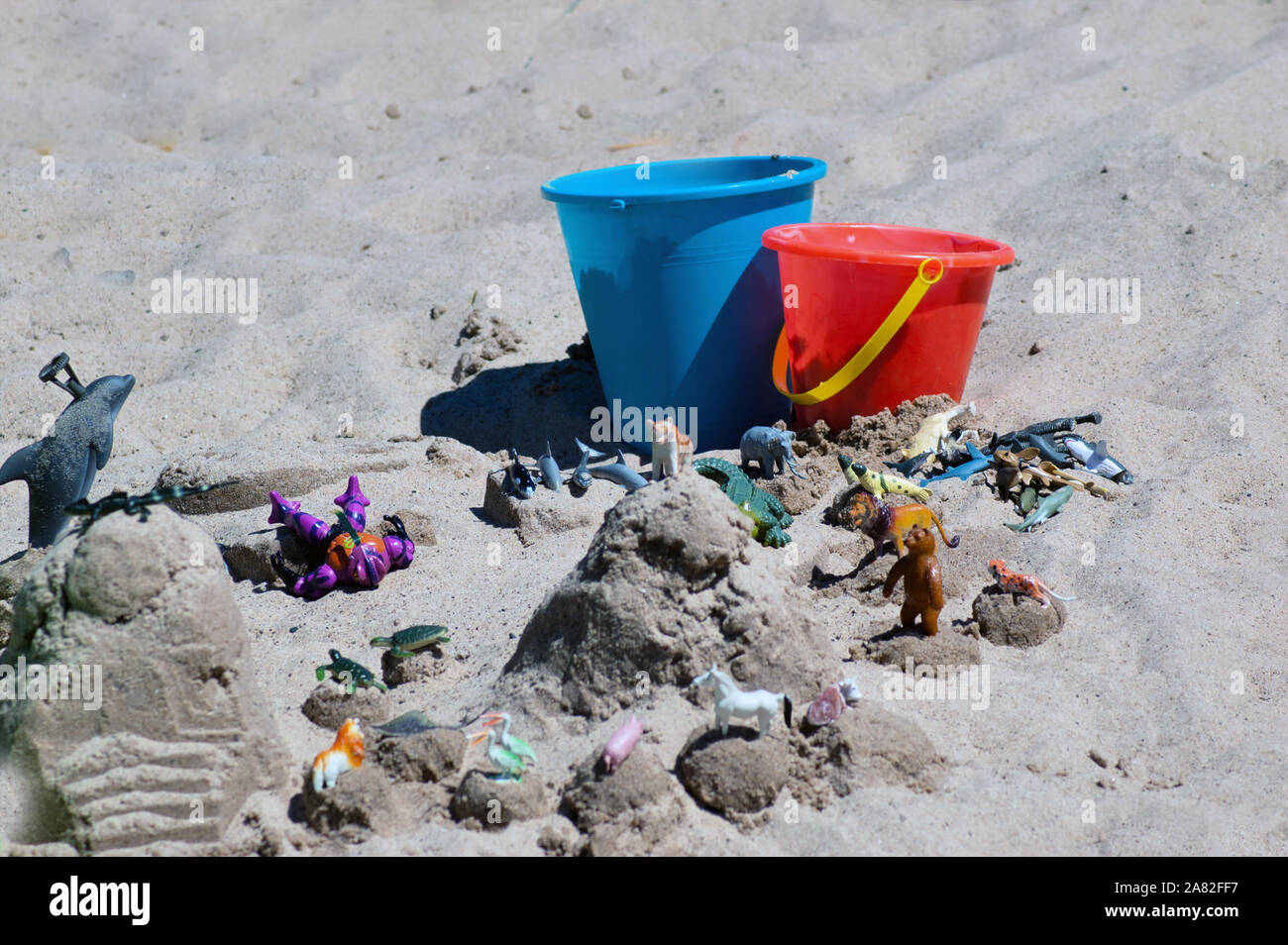 Bright, colorful plastic toys are arranged in the sand to create a ...