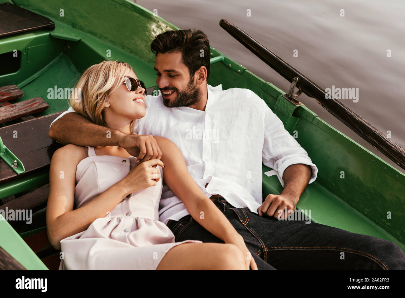 happy young man embracing pretty girlfriend while sitting in boat Stock ...