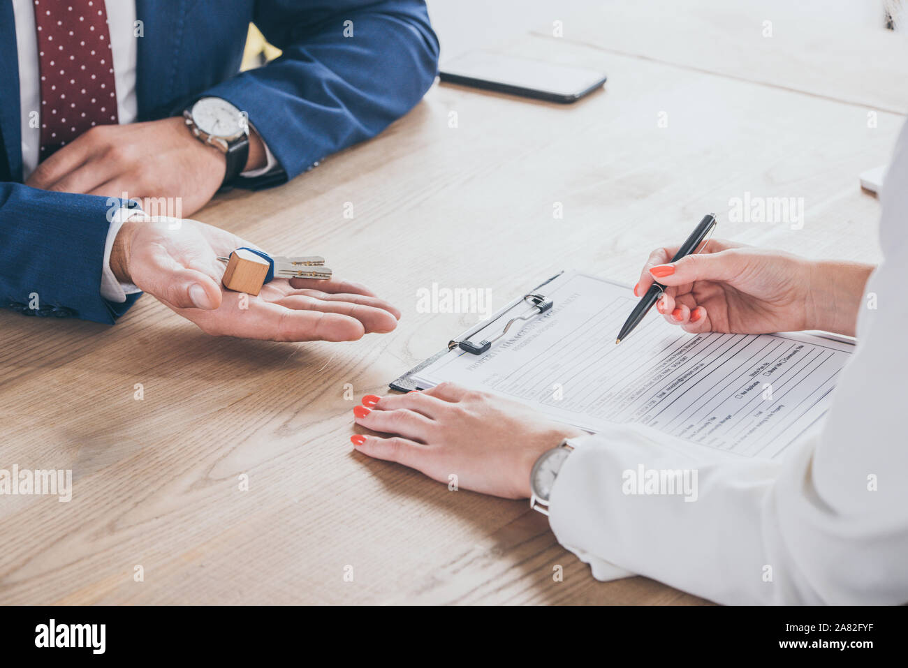 partial view of businessman holding house keys near man signing ...