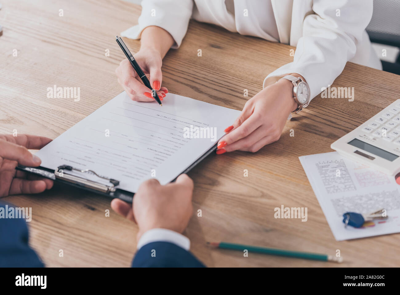 cropped view of businessman holding clipboard and woman signing ...