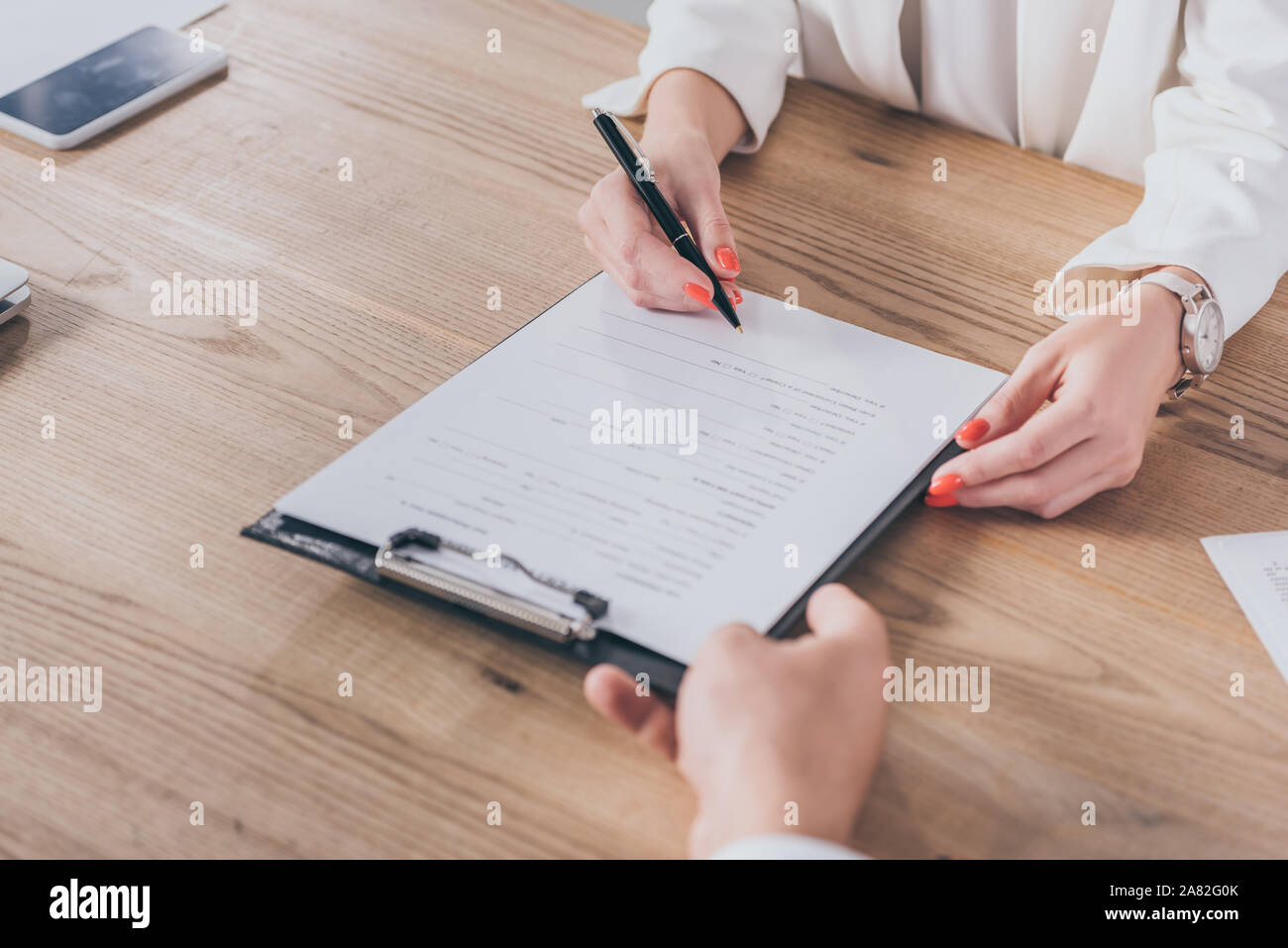 partial view of businessman holding clipboard and woman signing ...