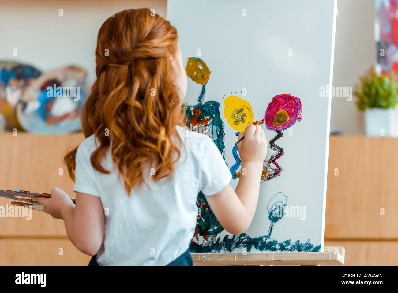 back view of redhead child painting on canvas in art school Stock Photo - Alamy