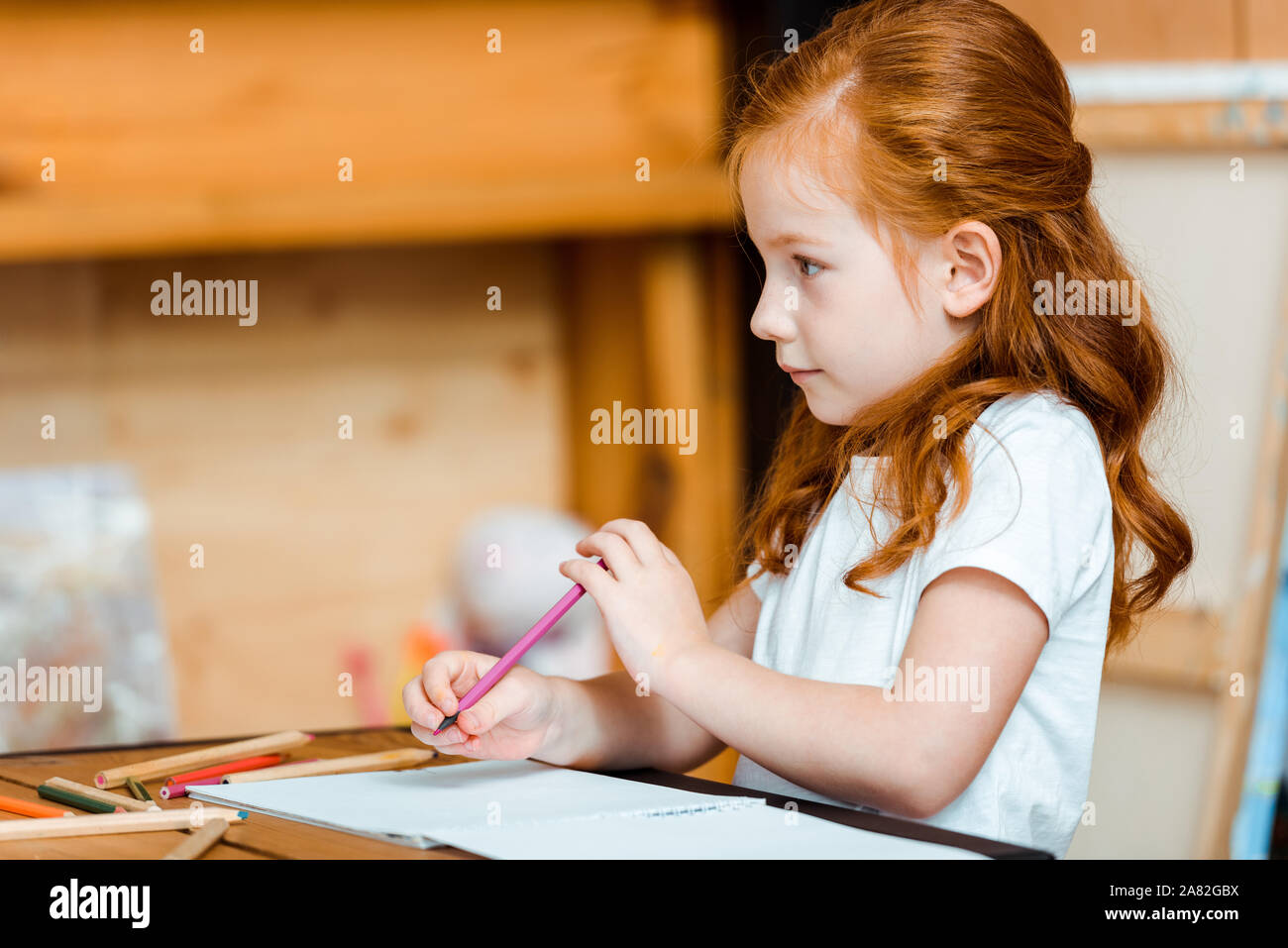 cute redhead kid holding color pencil near paper in art school Stock ...