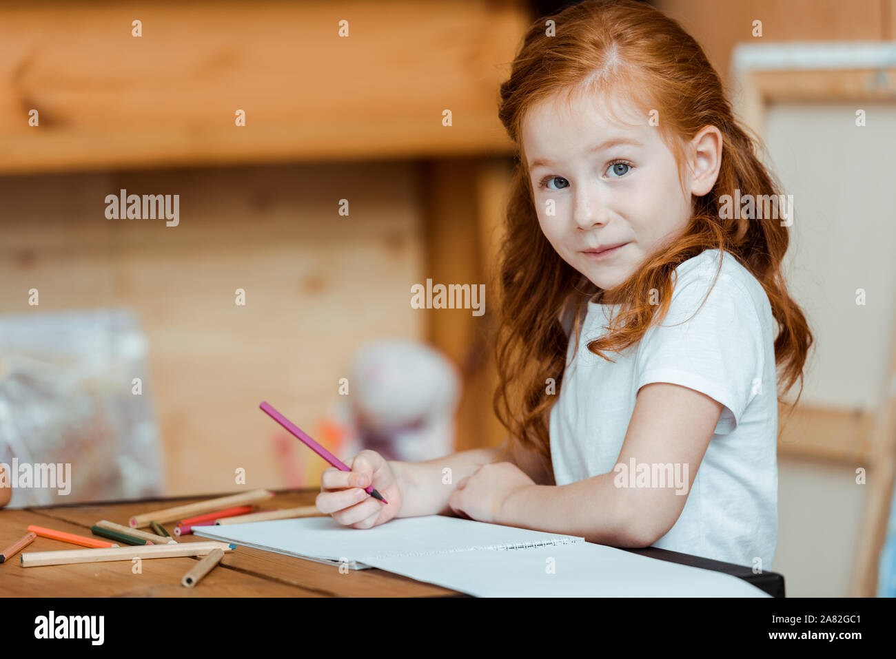 cute redhead child holding color pencil and looking at camera Stock Photo - Alamy