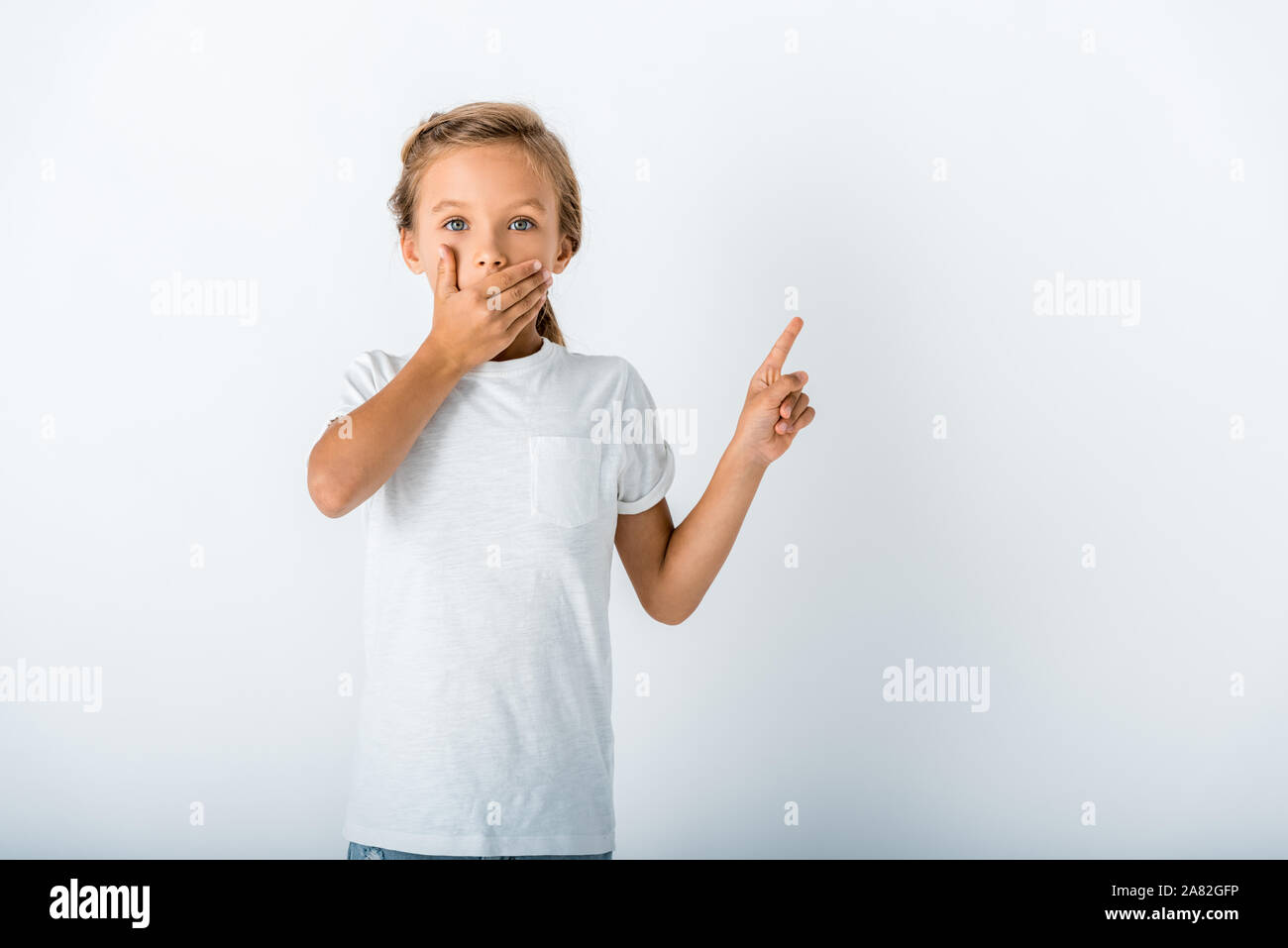 shocked kid covering face while looking at camera and pointing with ...