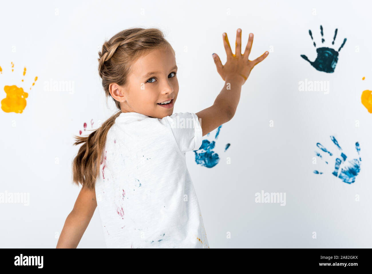 cheerful kid putting hand near hand prints on white Stock Photo - Alamy