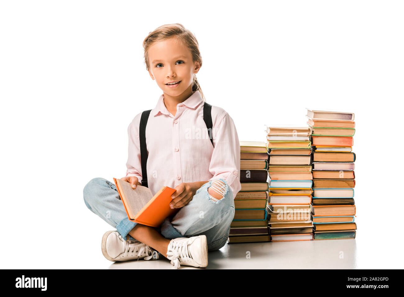happy kid sitting with crossed legs near books on white Stock Photo - Alamy