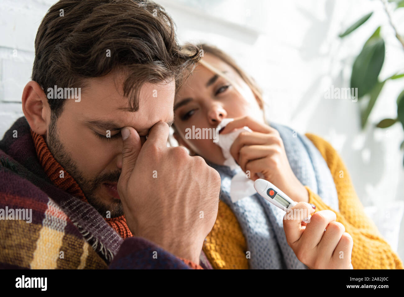 sick couple with fever holding thermometer and napkins in bed Stock ...