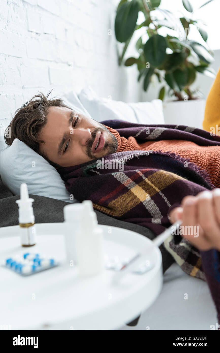 Sick man lying in bed with medicines on table at home Stock Photo - Alamy