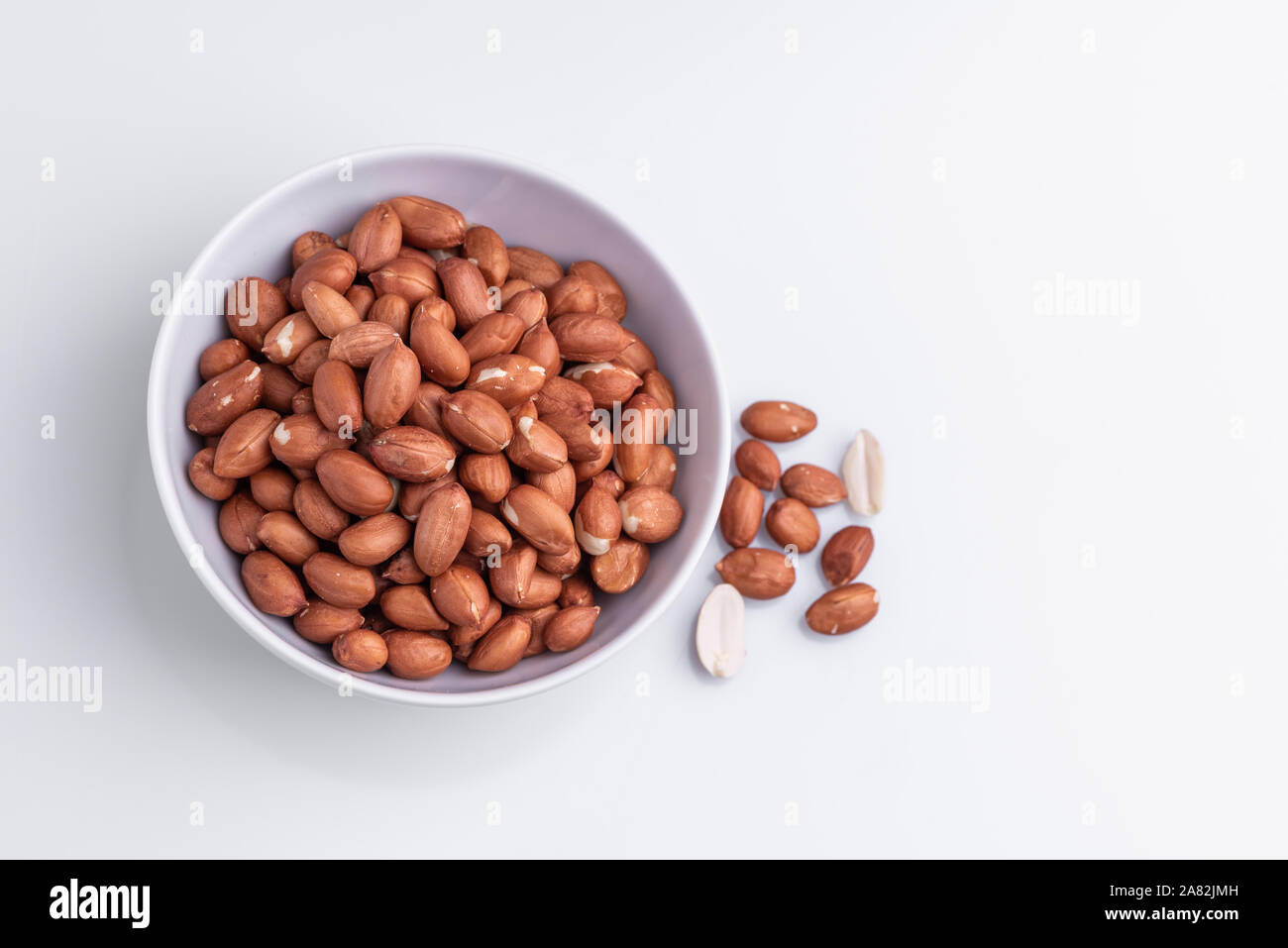 Raw shelled whole peanuts in a white bowl, isolated on white background ...