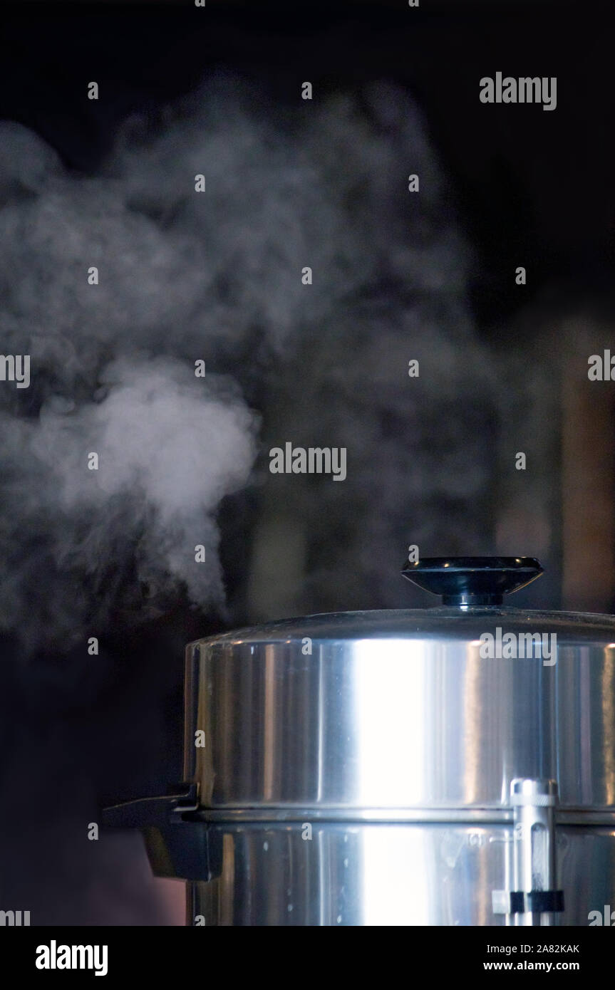 closeup of a large commercial coffee pot with steam coming out the top ...