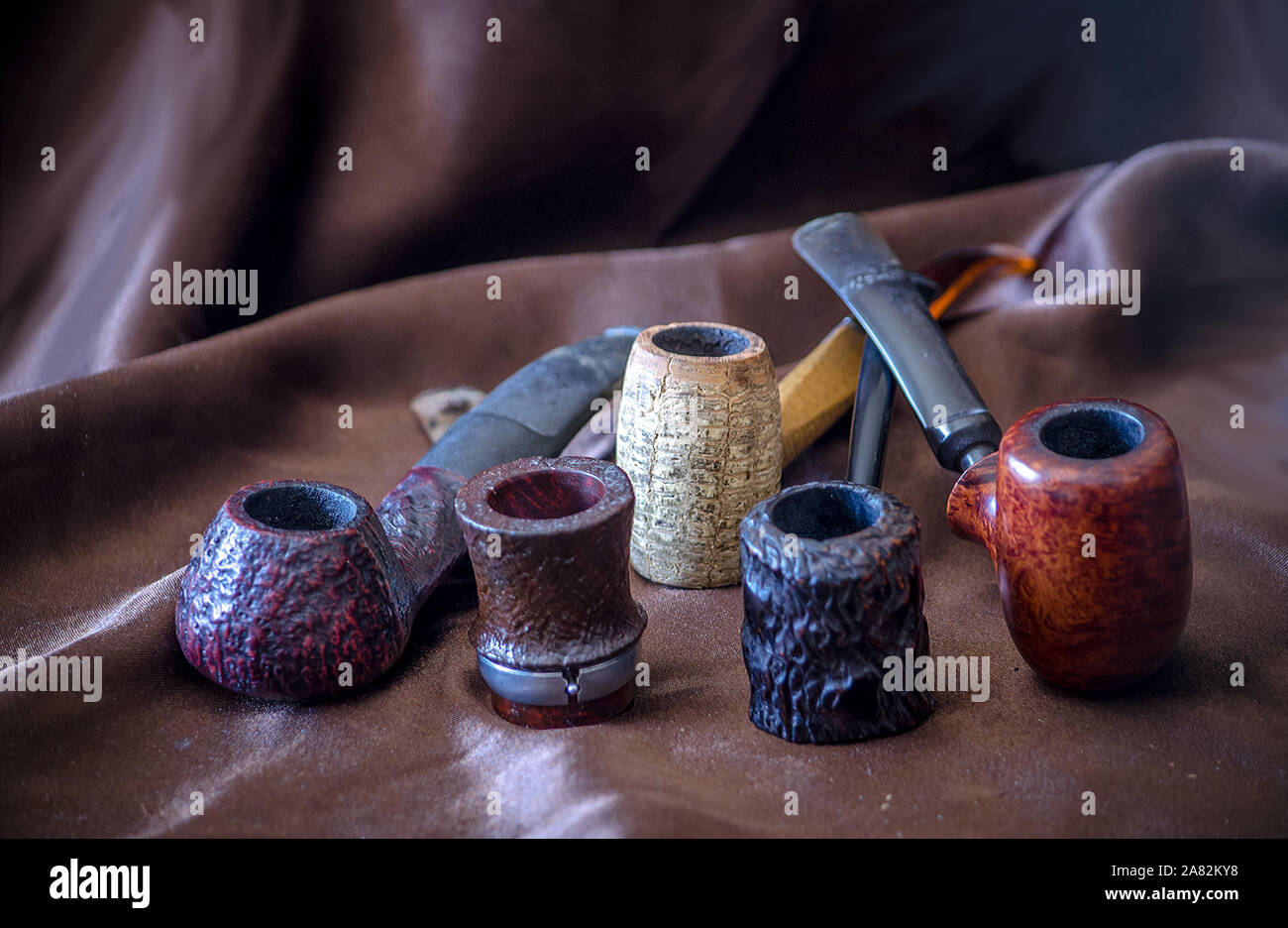 collection of rustic pipes on a brown silk backdrop Stock Photo - Alamy
