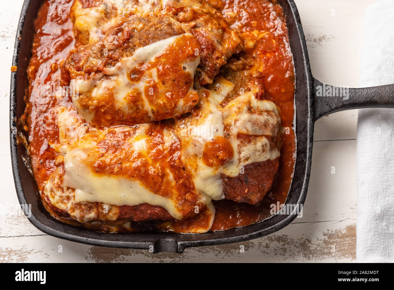 Parmegiana Steak also known as Filet Parmegiana in a black iron pan on ...