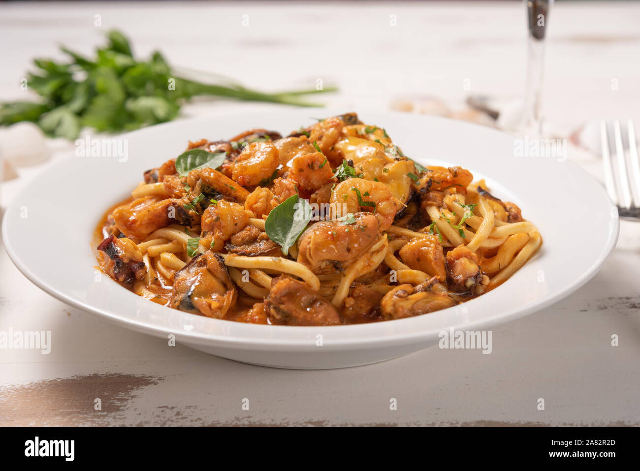 Pasta with sea fruit in white plate on a white wooden background, soft ...