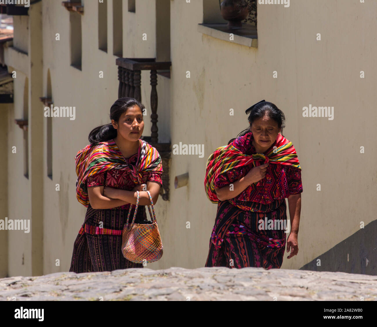 Two Quiche Mayan women, mother and daughter, in traditional dress climb ...