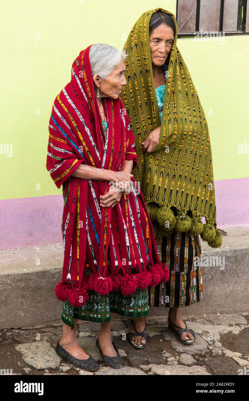 Two older women, a mother and daughter, in traditional dress, watch an ...