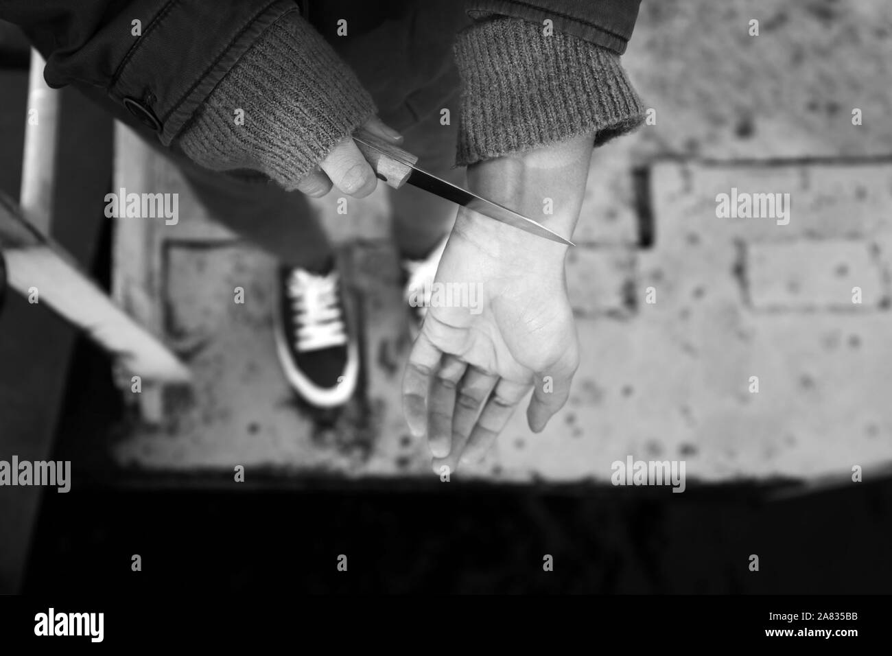 Black and white photo of woman cutting veins with knife outdoors ...