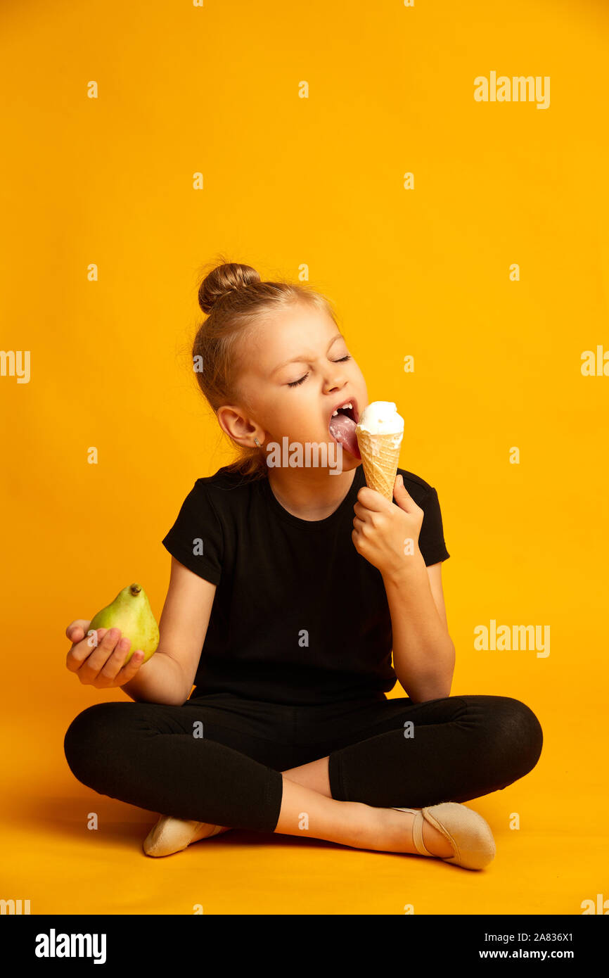 Cute little dancer girl choosing between apple and sweet ice-cream on ...