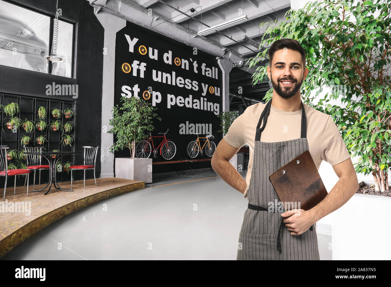 Handsome waiter with menu in modern cafe Stock Photo - Alamy