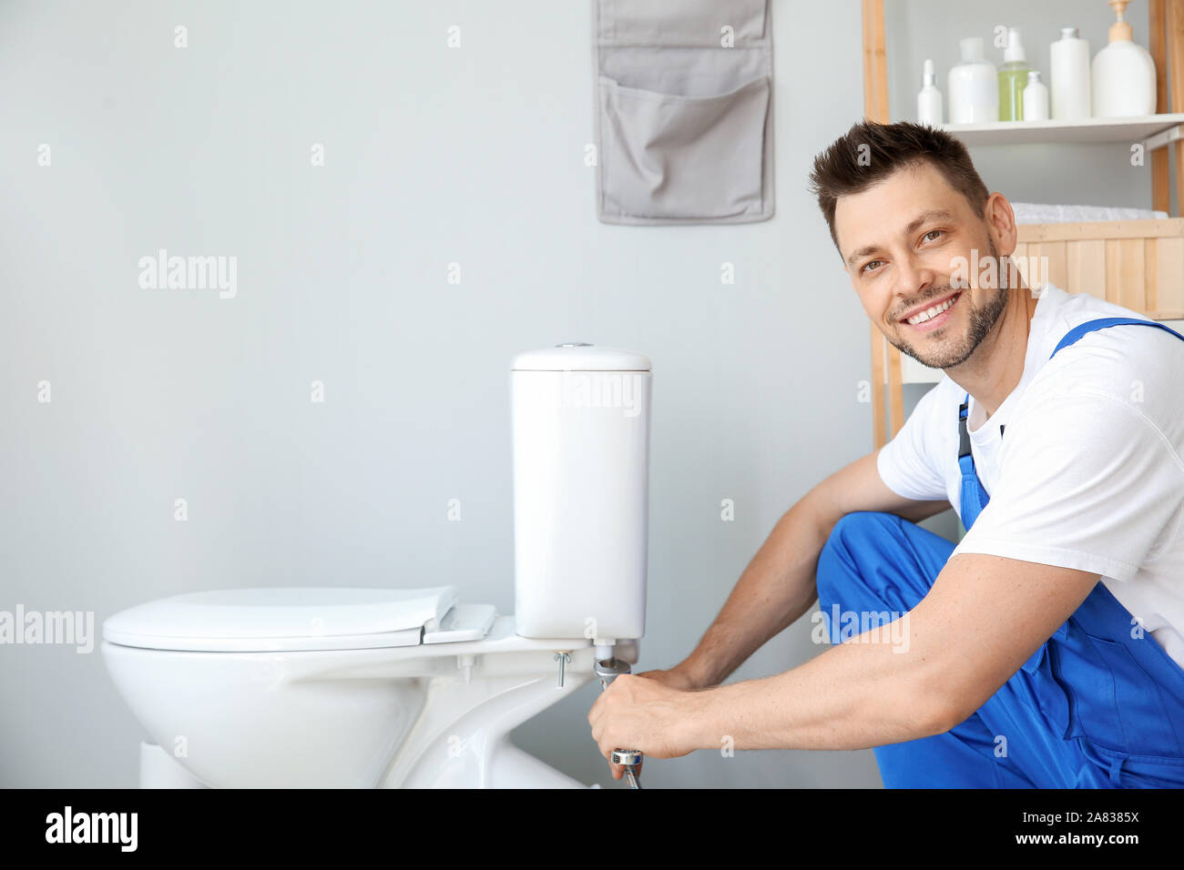 Plumber installing toilet in restroom Stock Photo - Alamy
