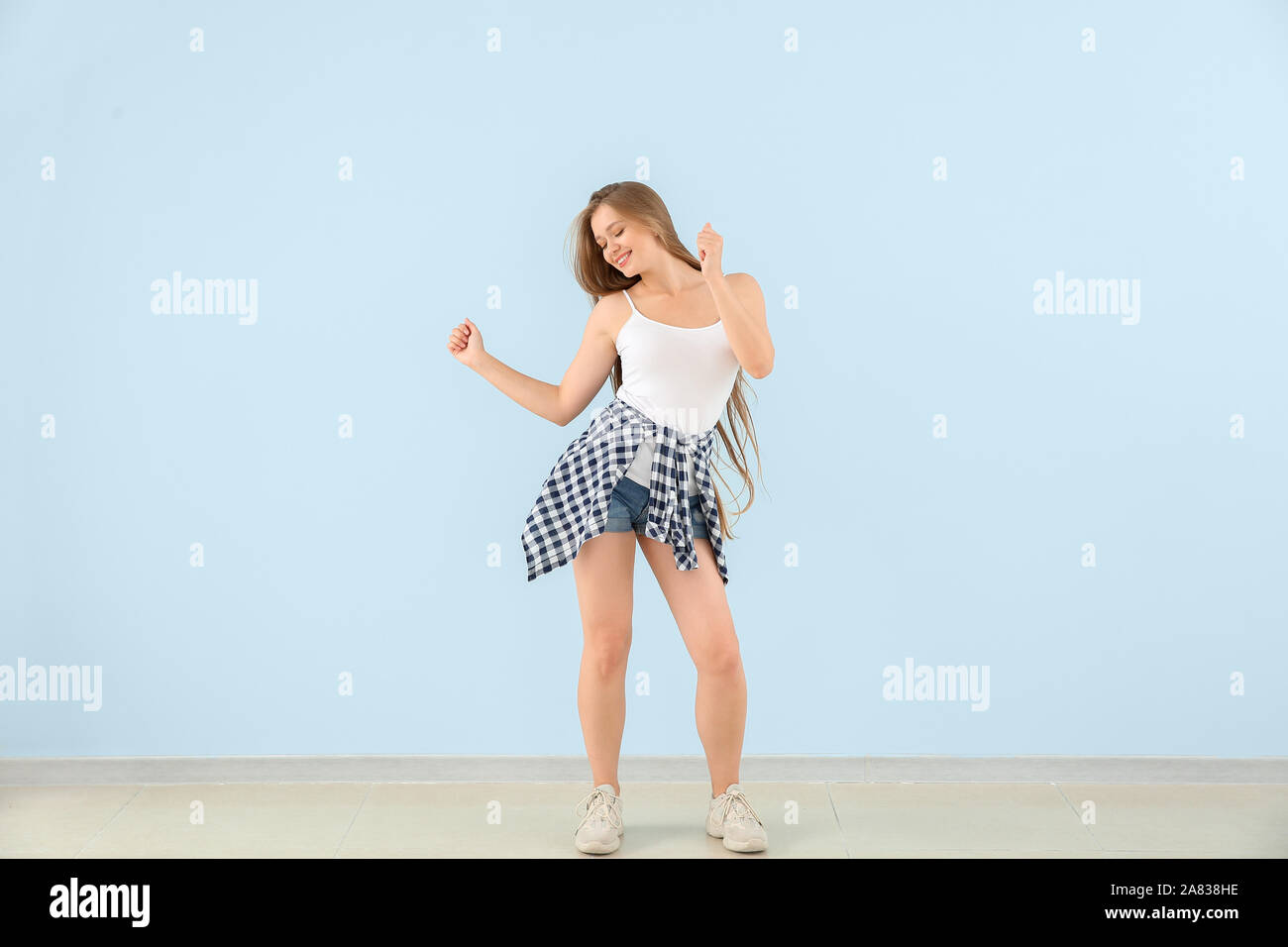 Cool young woman dancing against color wall Stock Photo - Alamy