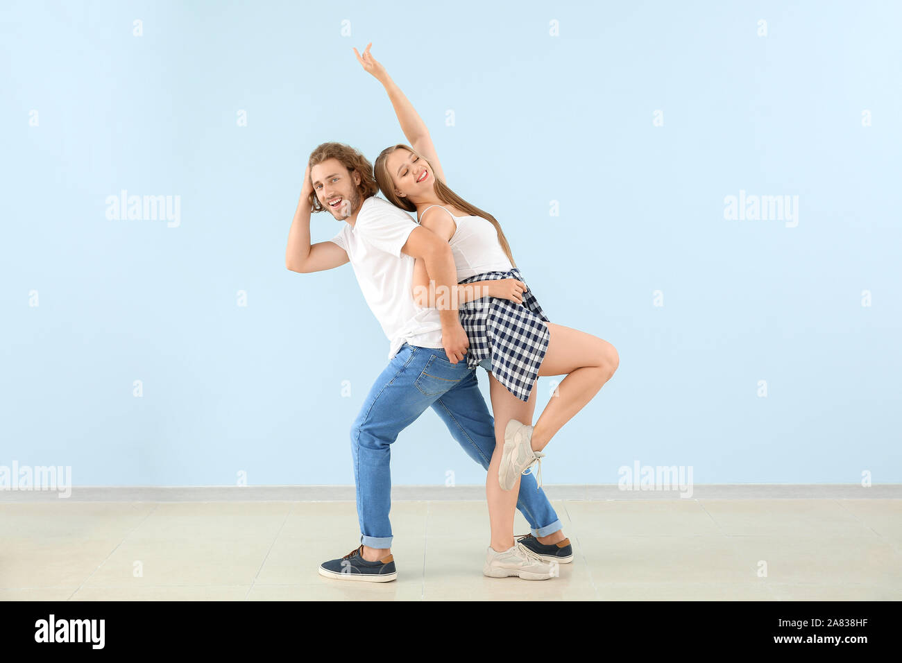 Cool young couple dancing against color wall Stock Photo - Alamy