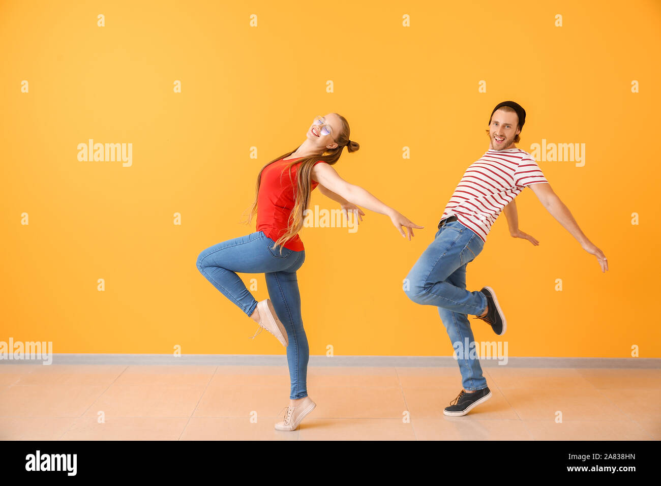 Cool young couple dancing against color wall Stock Photo - Alamy