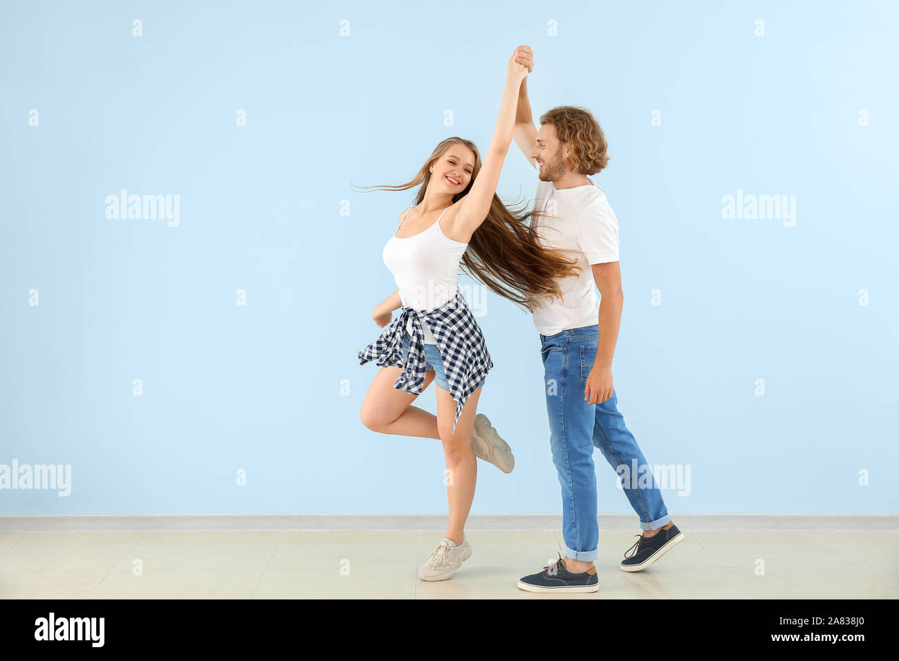 Cool young couple dancing against color wall Stock Photo - Alamy