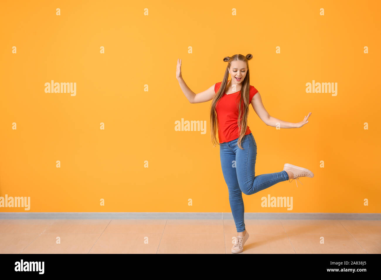 Cool young woman dancing against color wall Stock Photo - Alamy