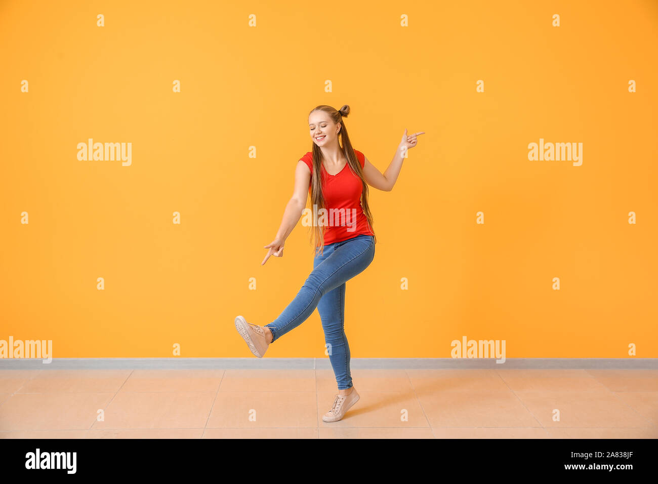 Cool young woman dancing against color wall Stock Photo - Alamy