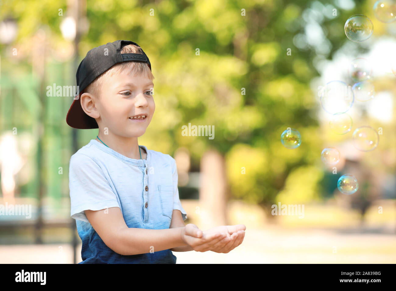 Cute little boy playing with soap bubbles in park Stock Photo - Alamy