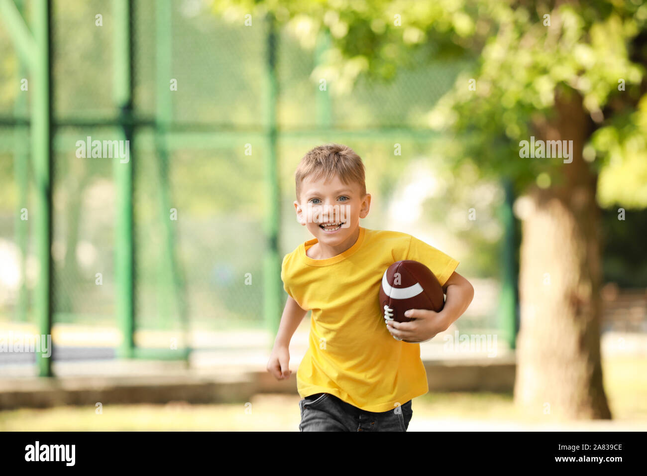 Running little boy with rugby ball in park Stock Photo - Alamy