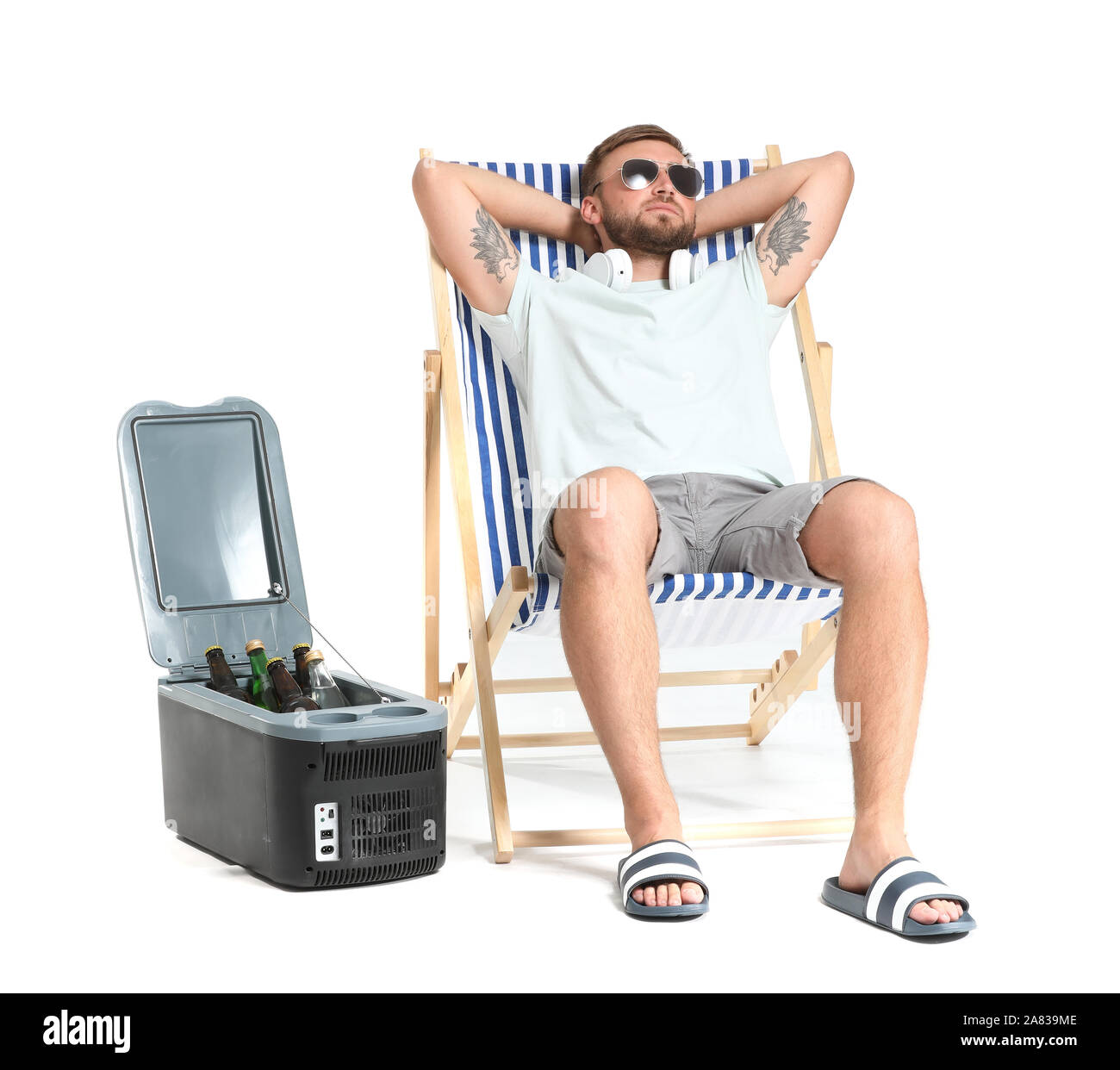 Handsome young man relaxing on sun lounger against white background ...