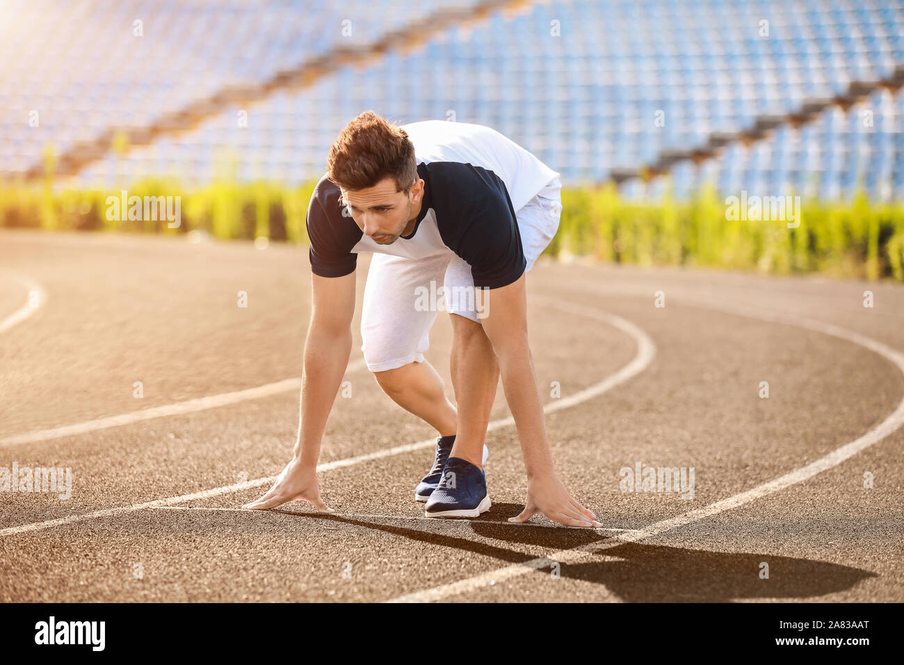 Sporty young man in crouch start position at the stadium Stock Photo ...