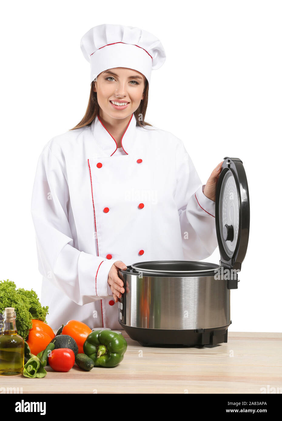 Female chef with modern multi cooker and products at table against ...