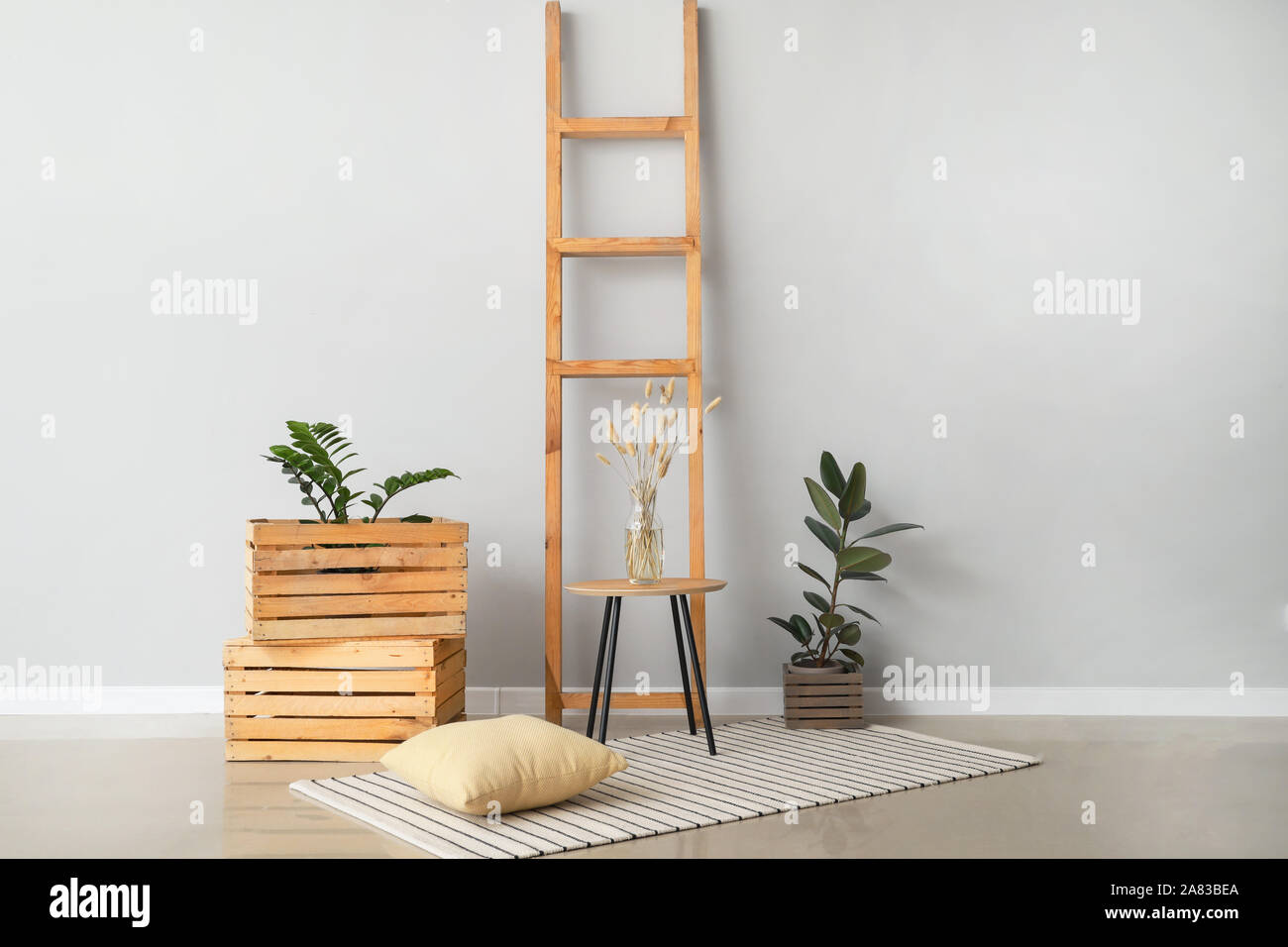 Table with wooden boxes and ladder near light wall in room Stock Photo ...