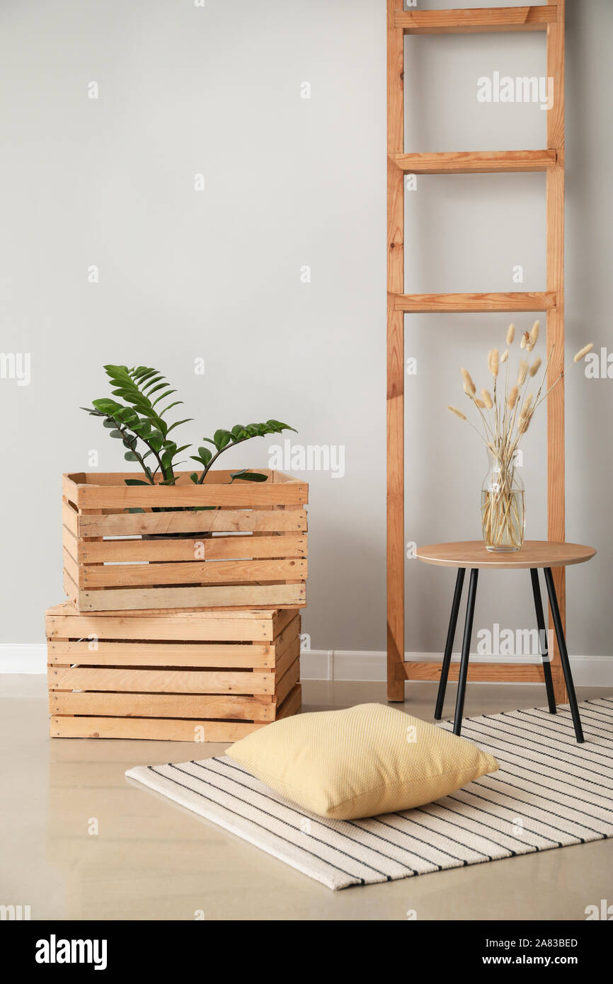 Table with wooden boxes and ladder near light wall in room Stock Photo ...