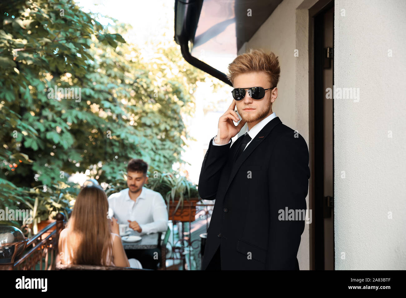 Bodyguard protecting young couple in cafe Stock Photo - Alamy