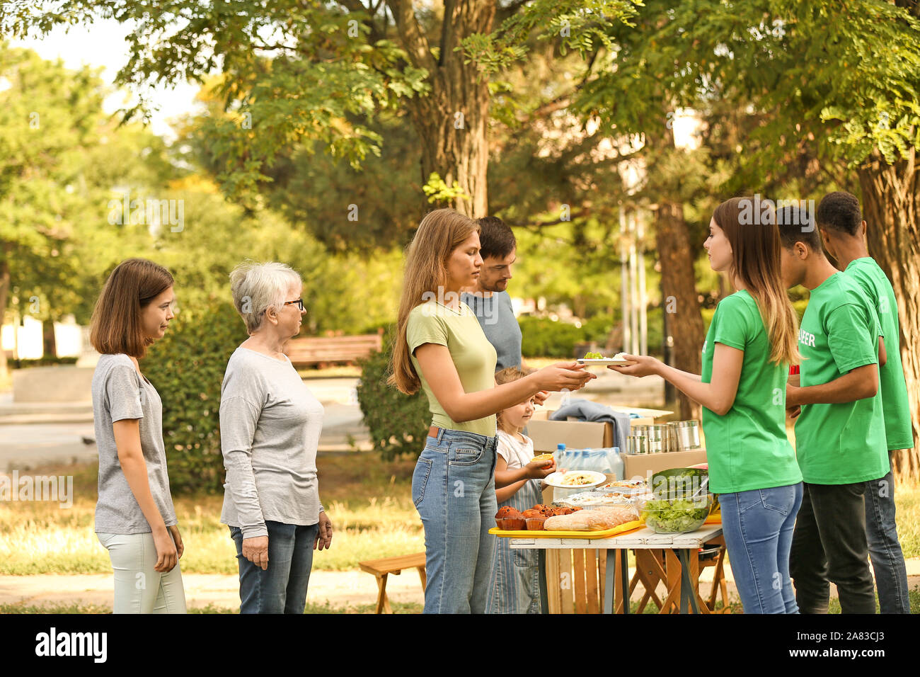 Young volunteers giving food to poor people outdoors Stock Photo - Alamy