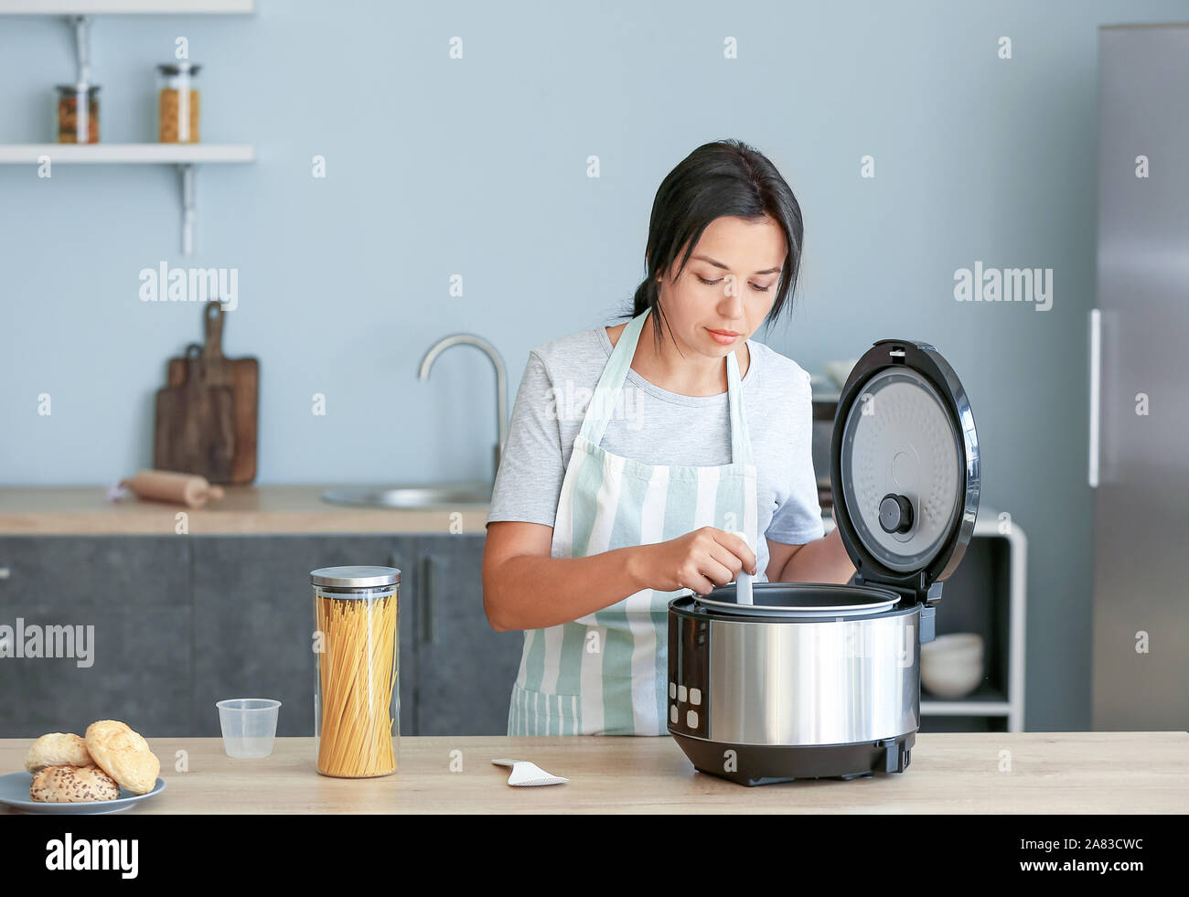 Beautiful woman using multi cooker at home Stock Photo - Alamy