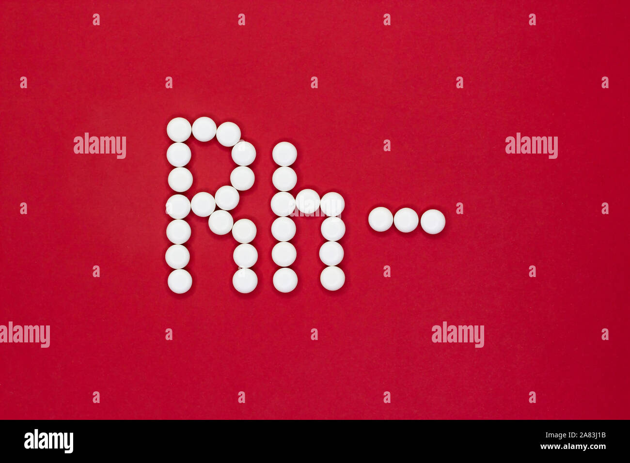 Negative Rh factor. Rh- inscription made of white pills on a red ...
